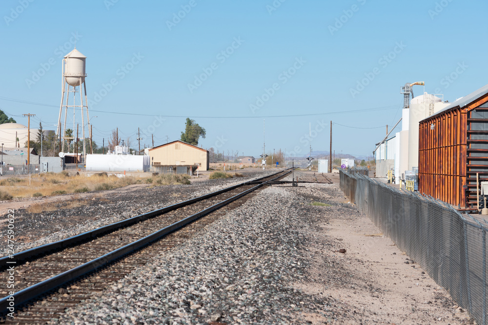 Railroad track in a village with commercial buildings and a water tower ...