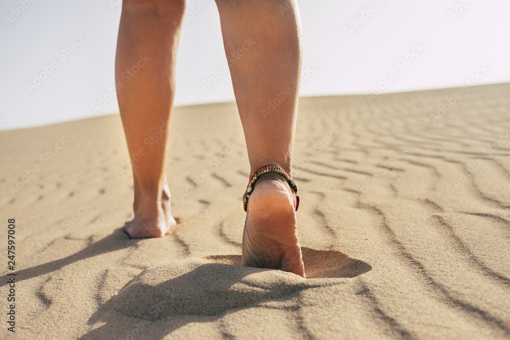 Woman walking barefoot on desert dunes leaving footprints in the sand ...