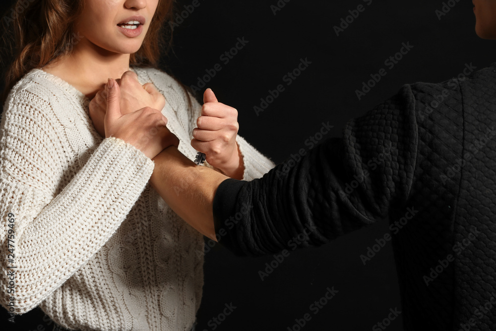 Young woman defending herself from attack by thief on dark background ...