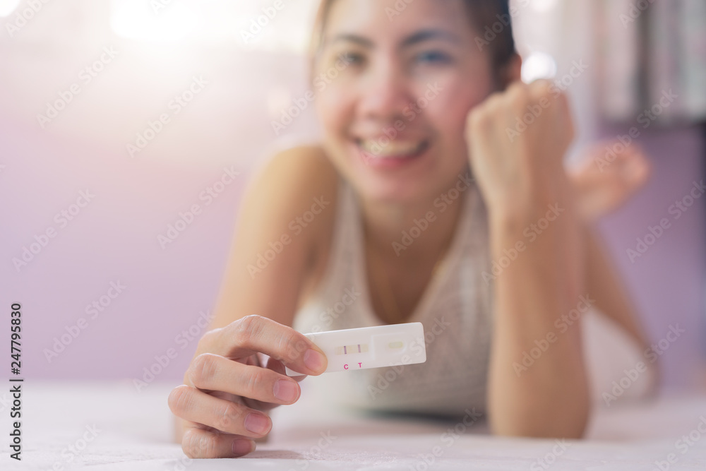 Pregnant asia woman in white dress hole and show a pregnancy test strip ...