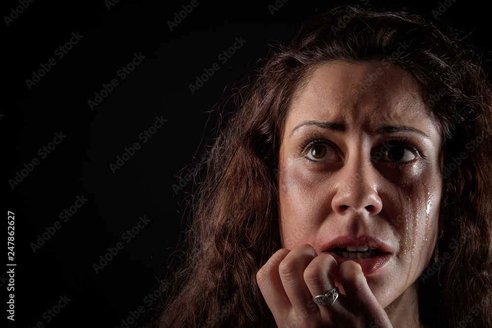 closeup portrait of a scared woman crying with bruises and wounds marks ...