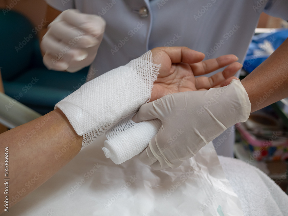 Doctor is bandaging upper limb of patient after cleaning the wound from ...
