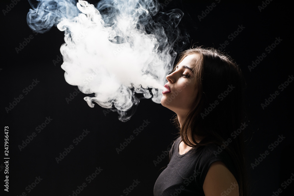 Young woman vaping and blowing smoke of electronic cigarette isolated ...