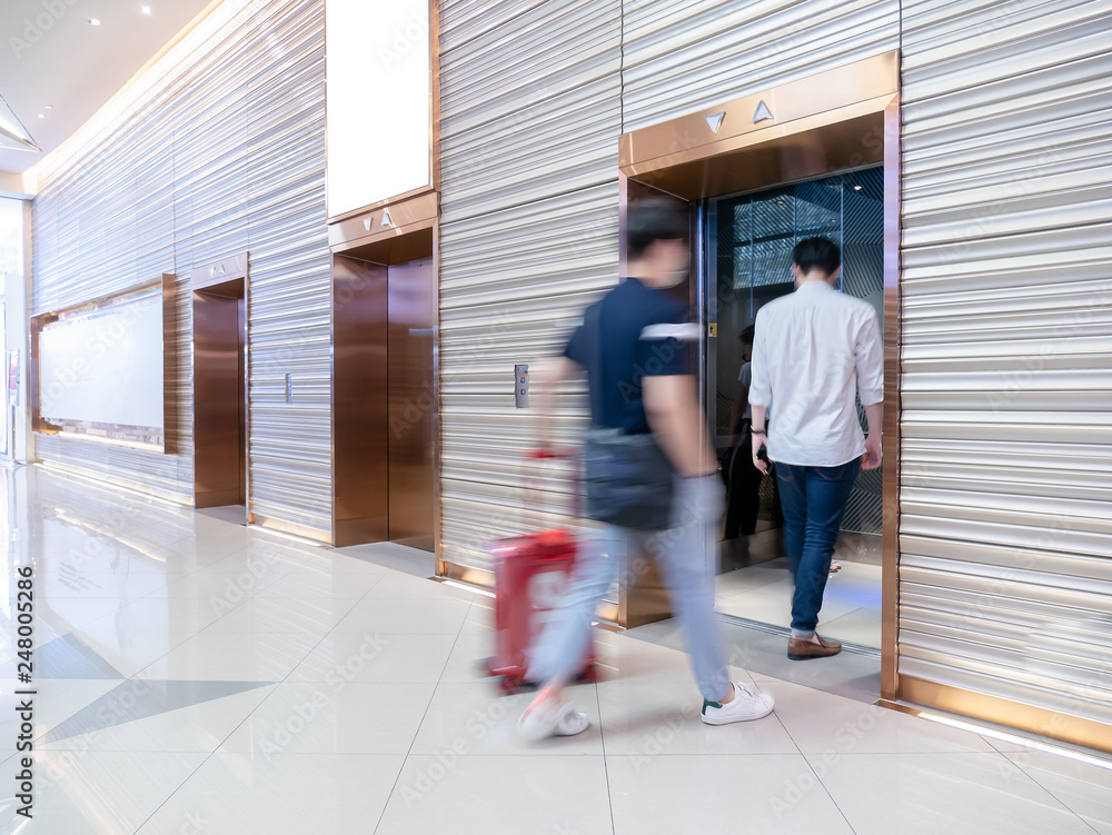 People are walking in office past elevators, Modern steel elevator ...