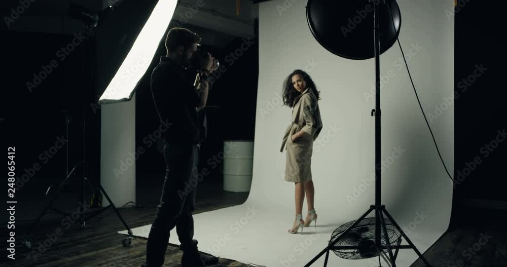 Hot professional female model posing to the camera of the man photographer in the studio with ...