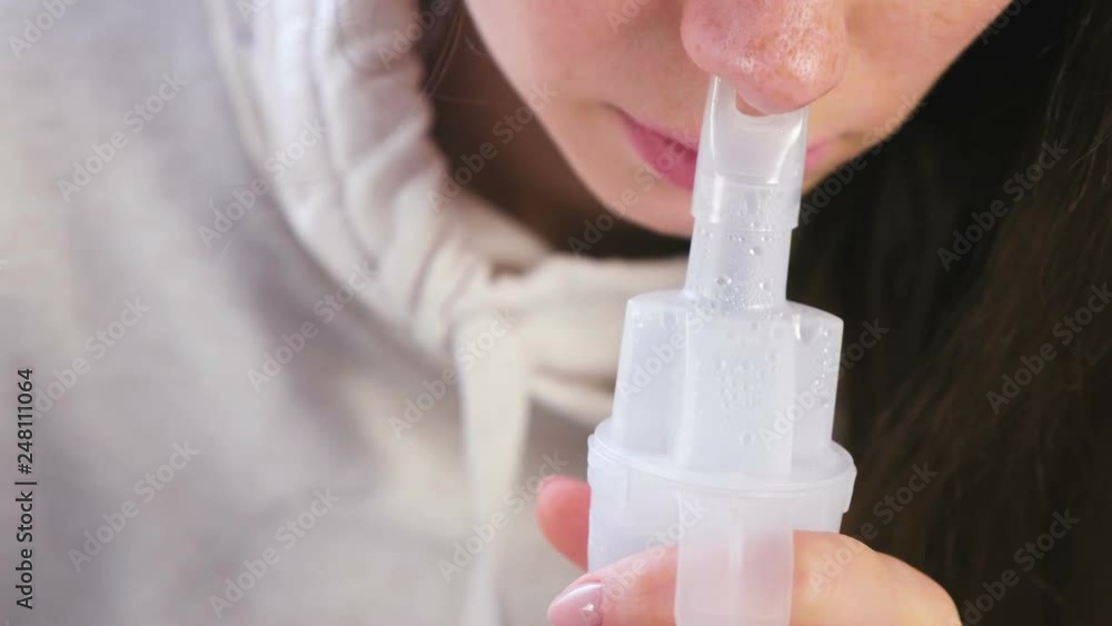 Use nebulizer and inhaler for the treatment. Young woman inhaling ...
