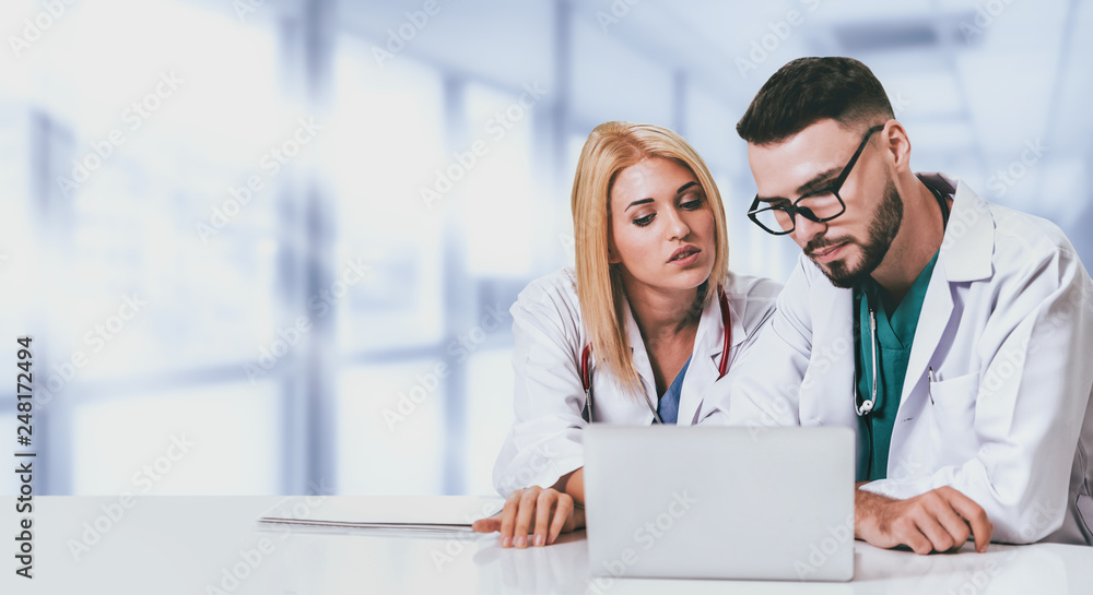 Doctor working with laptop computer at the office while having ...