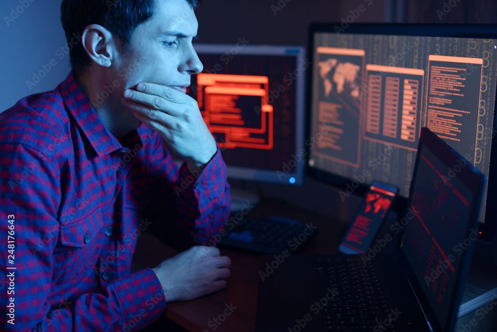 Hacker thinking about the problem of hacking on the background of screens with codes in neon ...