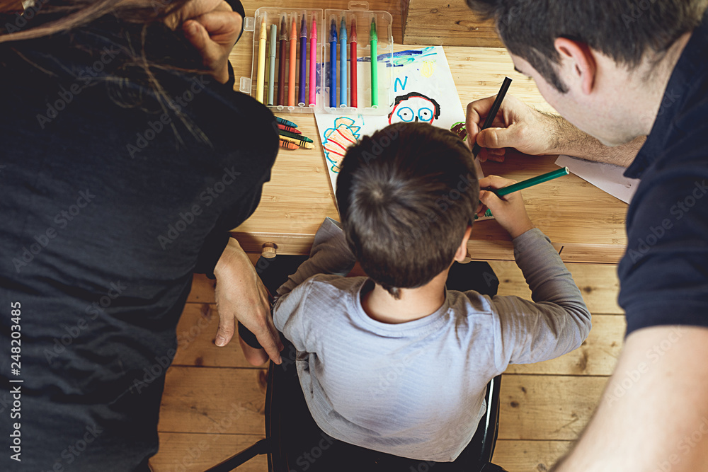 Child painting a picture at home with his parents. Couple assisting ...