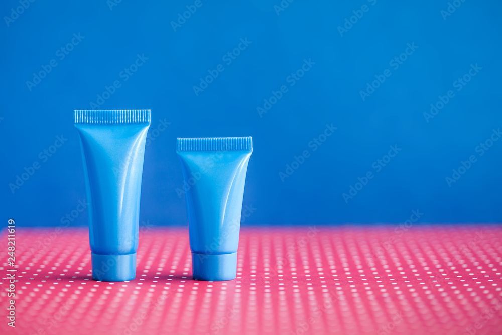 Minimal packaging design. Two blue cosmetic tubes on pink polka dot ...