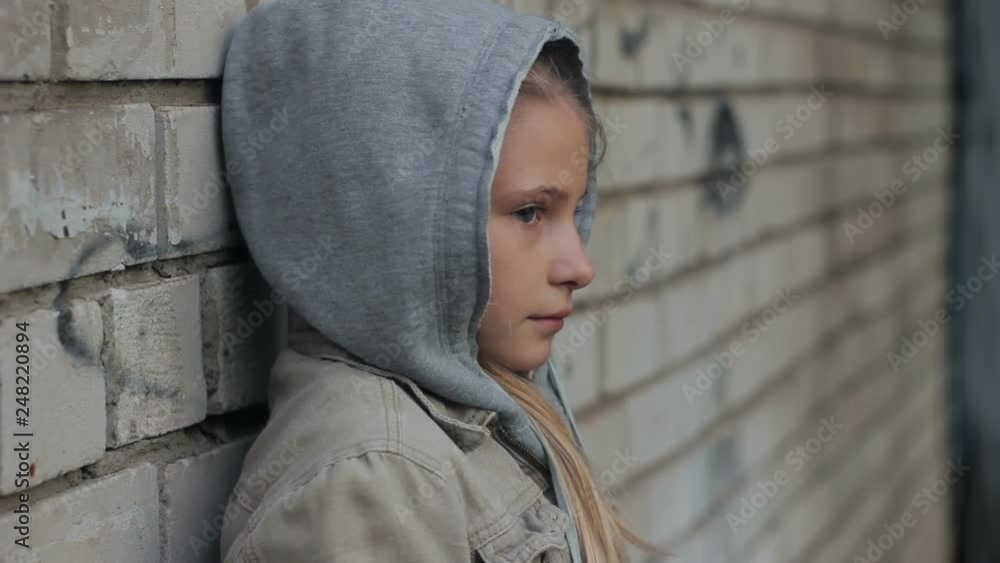 Sad pensive preteen girl standing leaning head against brick wall. Side ...