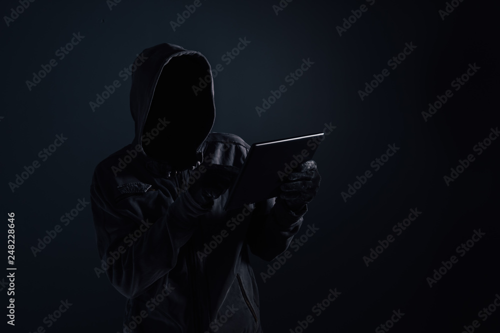 Hooded computer hacker with obscured face using digital tablet Stock ...