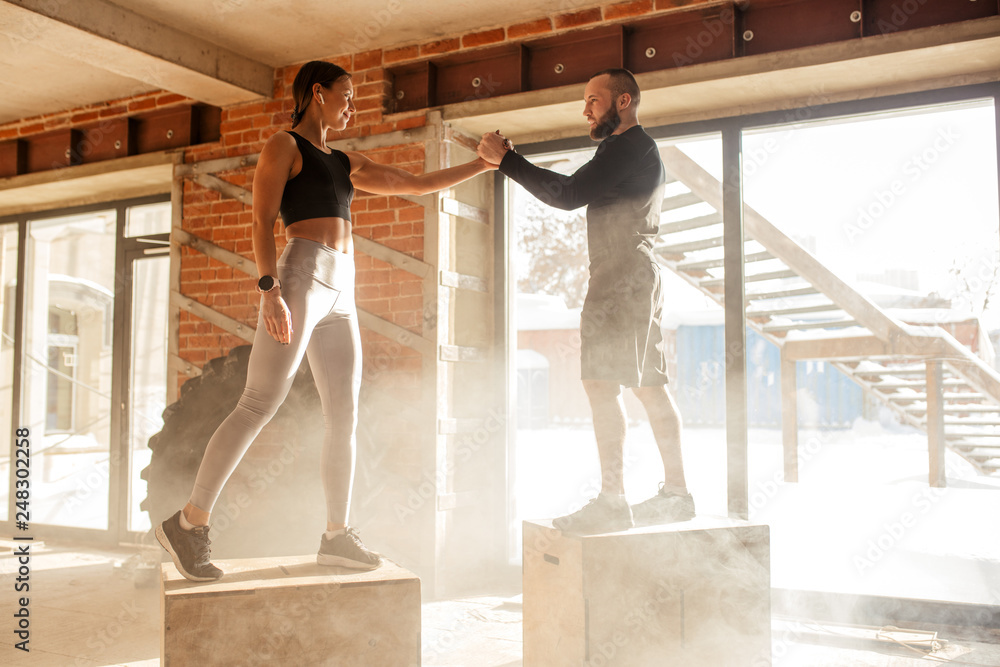Caucasian sportive female and male athlets are performing box jumps at ...