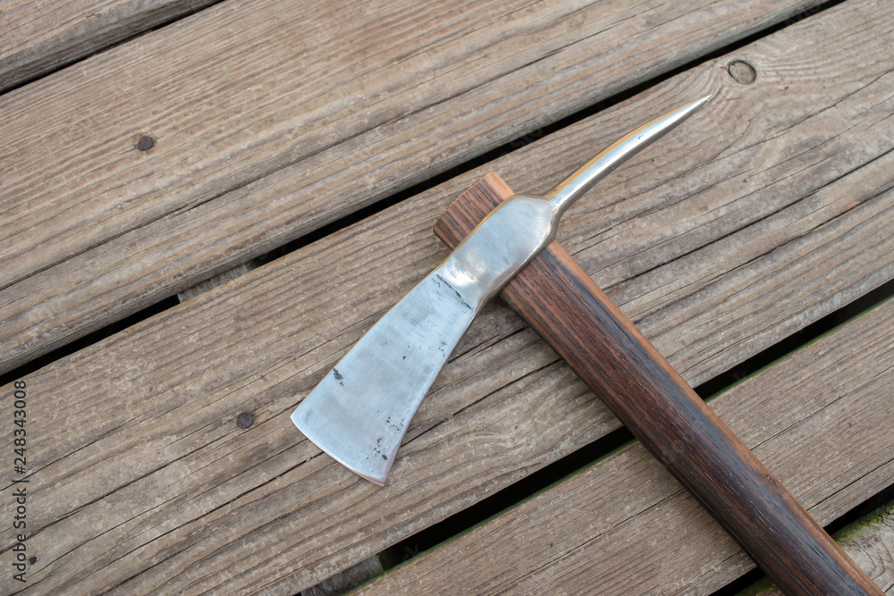 A handmade war tomahawk displayed outdoors on the wooden deck. A ...