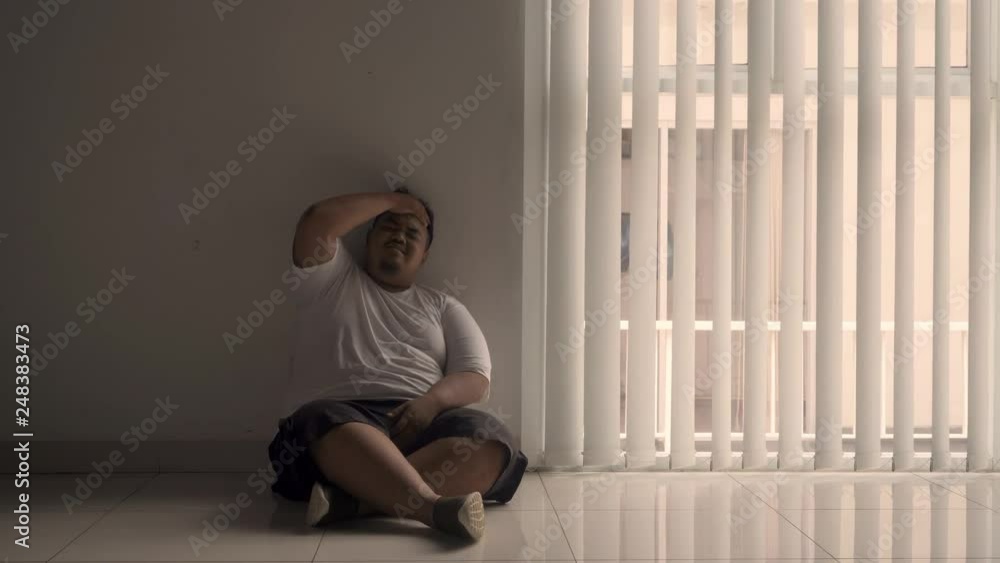 Stressful overweight man sitting next to the window while thinking his ...