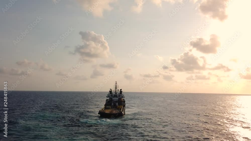 Anchor handling vessel pulling an anchor and wire to move an oil ...
