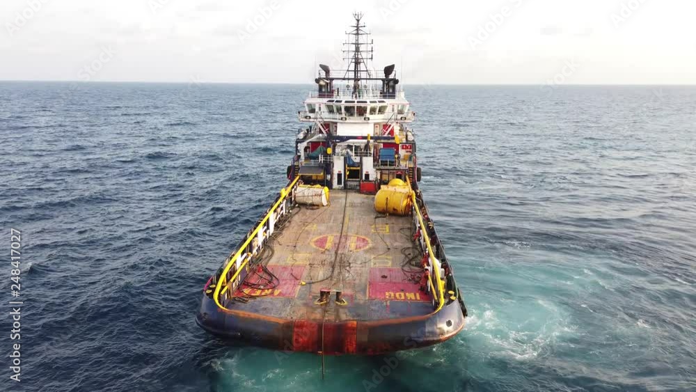 Anchor handling vessel pulling an anchor and wire to move an oil ...