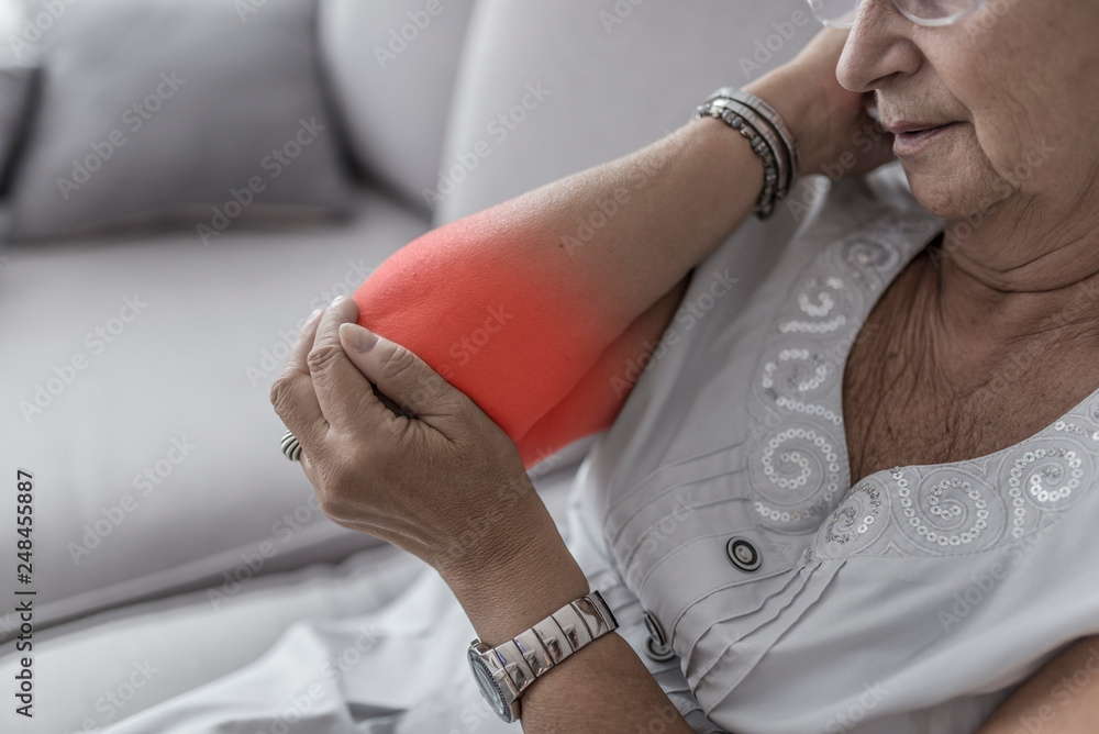 Old woman hand holding her elbow suffering from elbow pain. File ...