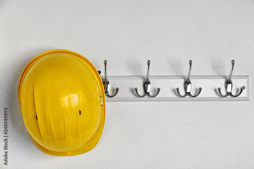 Hard hat hanging on white wall. Safety equipment Stock Photo | Adobe Stock
