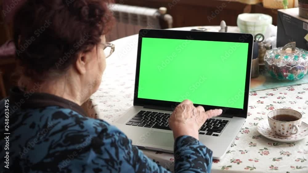 A smillng senior elderly woman uses a computer tablet device. Green ...