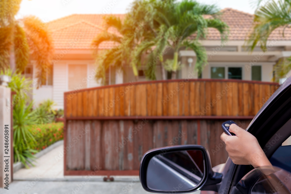 Woman in car, hand using remote control to open the automatic gate with ...
