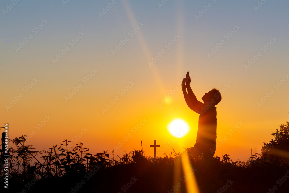 human praying to the GOD while holding a crucifix symbol with bright ...