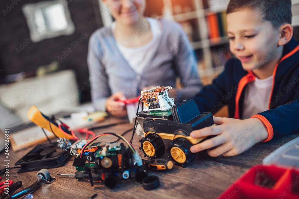 Happy smiling boy and girl constructs technical toy and make robot. Technical toy on table full ...