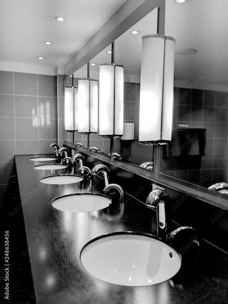 Row of shiny, contemporary, ceramic wash hand basins in front of a wall ...