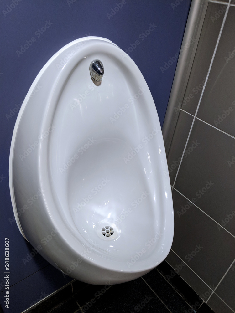 A shiny white porcelain urinal with purple medium density fibre board ...
