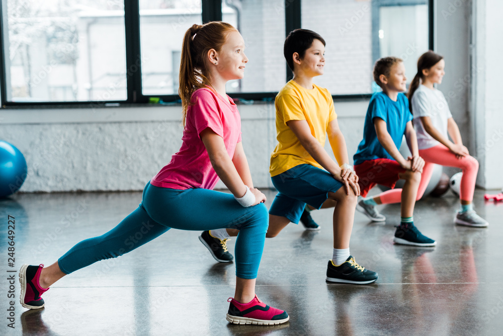 Group of cheerful kids doing stretching in gym Stock Photo | Adobe Stock