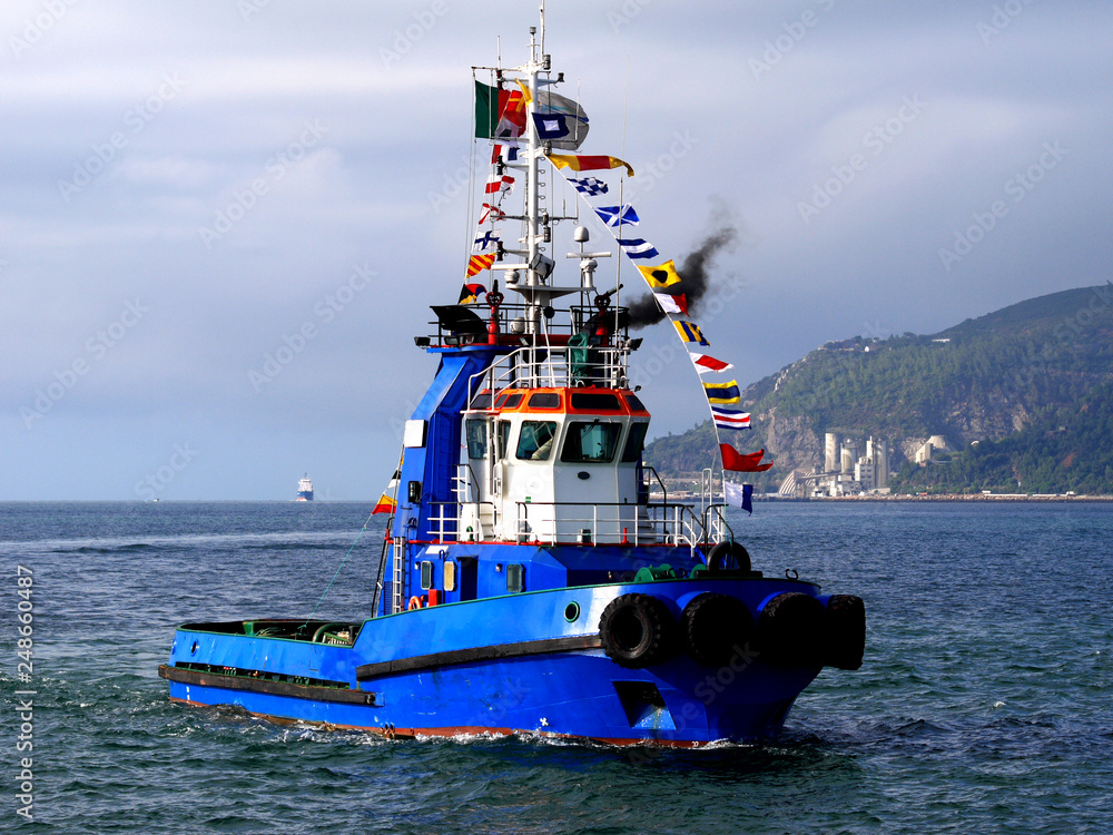 Harbour tugboat maneuvering in bay during maritime festival activities ...