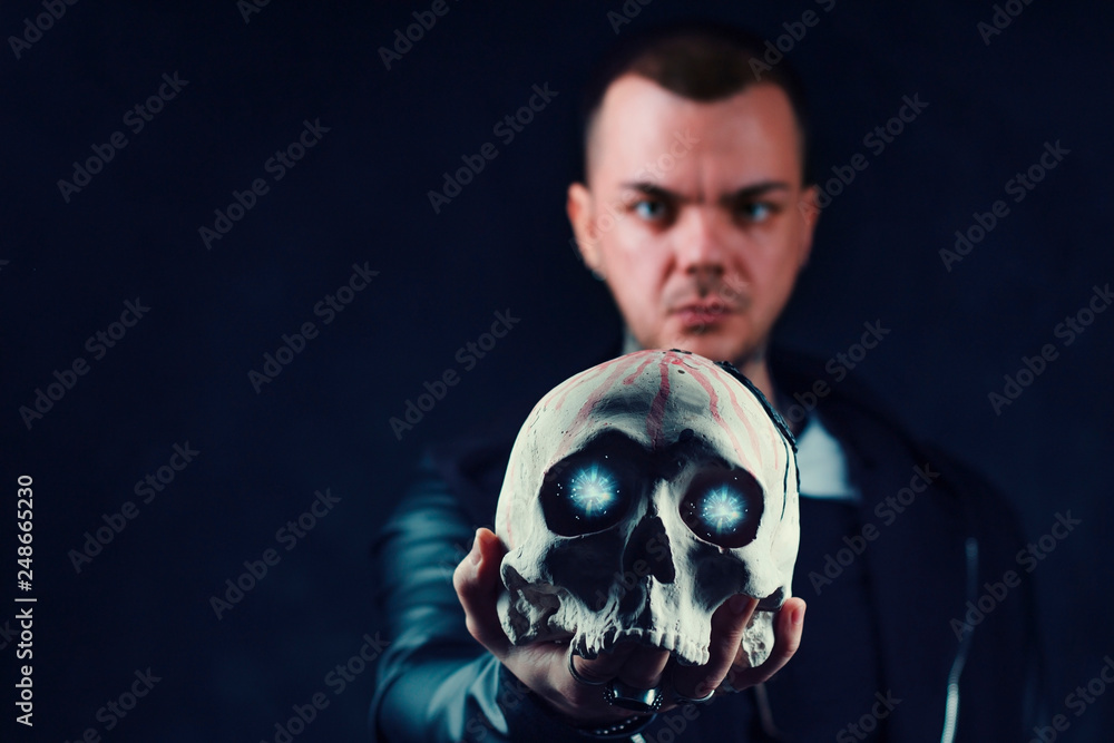 Strict guy stretches his hand forward, in his hand lies a skull on a ...