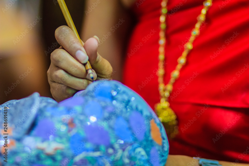Close up Thai woman artist in red Thai style dressed is painting the ...