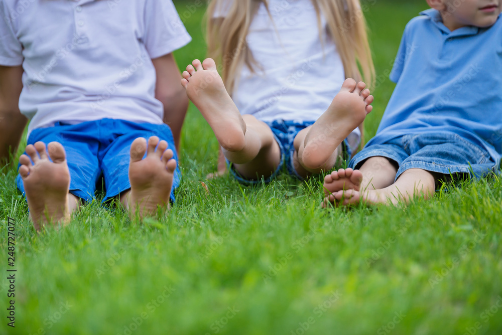 Happy children show their feet close up in the park. Barefoot on the ...
