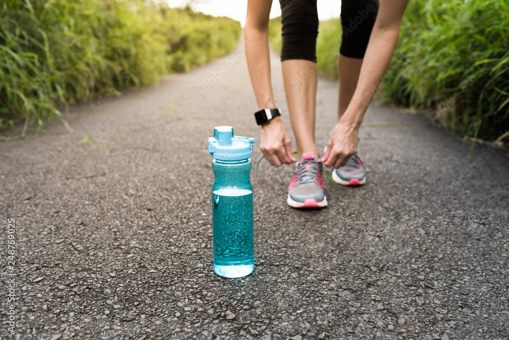 Water and health. female runner tying shoe next to water bottle. Stock ...