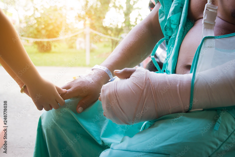 The sick father was at the hospital. The little boy held hands with ...