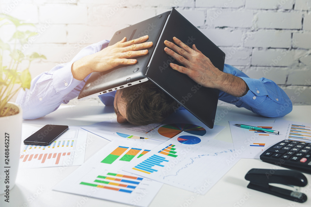 tired overworked office worker sleeping on the desk with laptop over ...