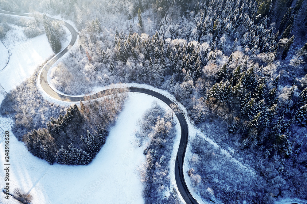 Aerial drone view of a curved winding road through the forest up in the ...