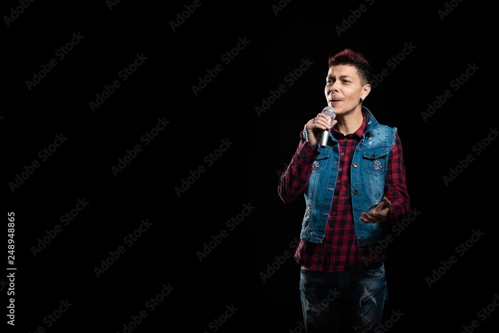 Woman singer with red hair in a denim suit with a microphone in her ...