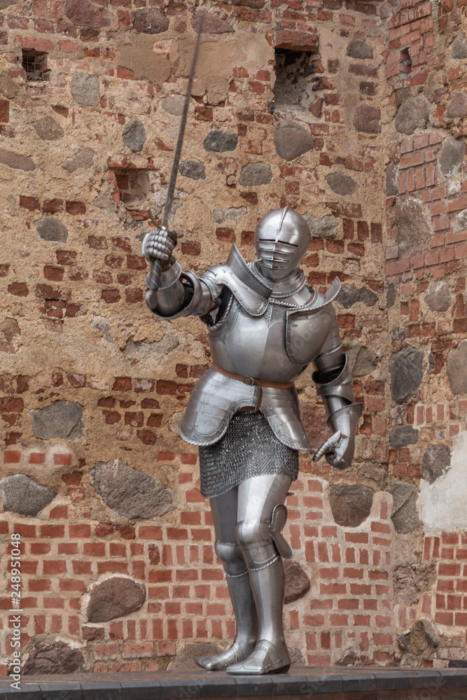 Knight in full armor with a sword against the background of the ancient ...