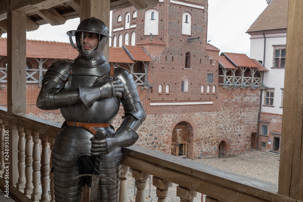 Knight in full armor with a sword against the background of the ancient ...