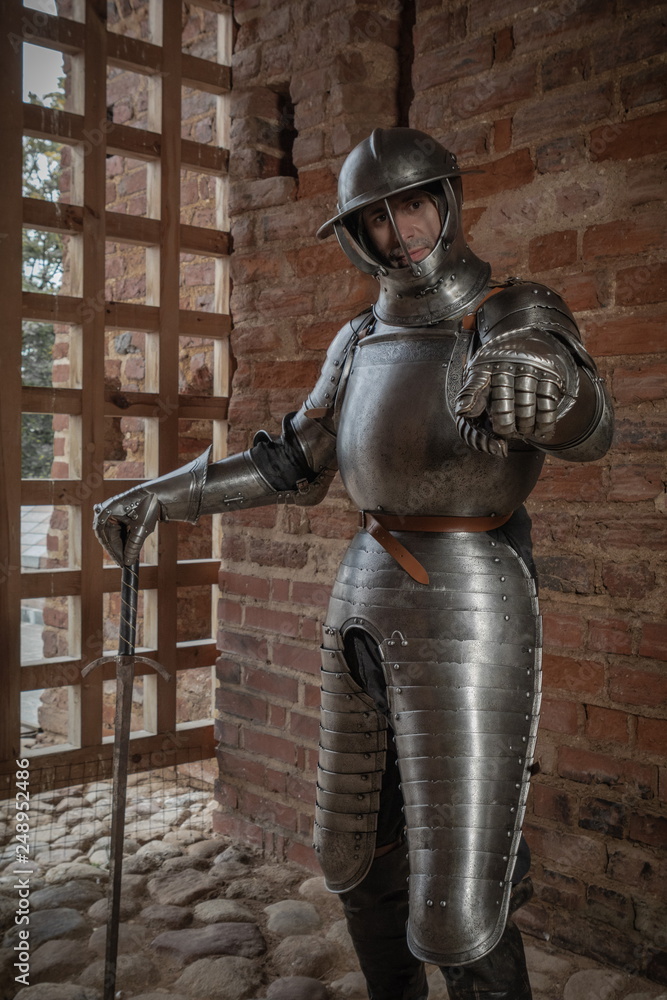 Knight in full armor with a sword against the background of the ancient ...