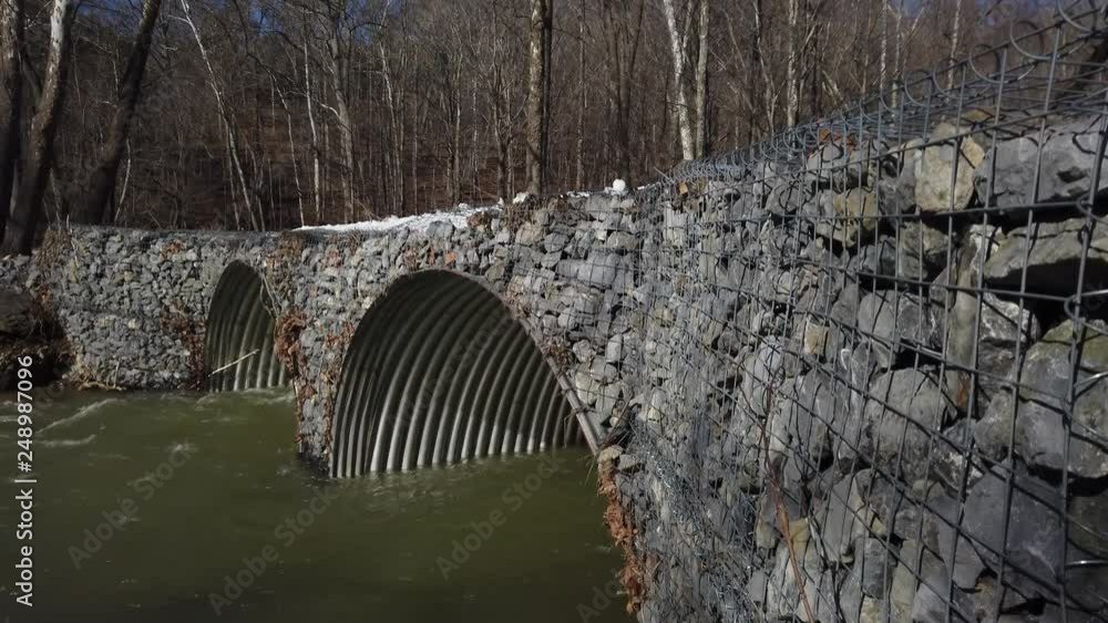 View of two large corrugated culverts serving as a bridge with snow and ...