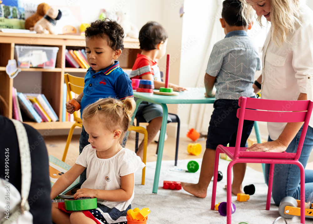 Nursery children playing with teacher in the classroom Stock Photo ...