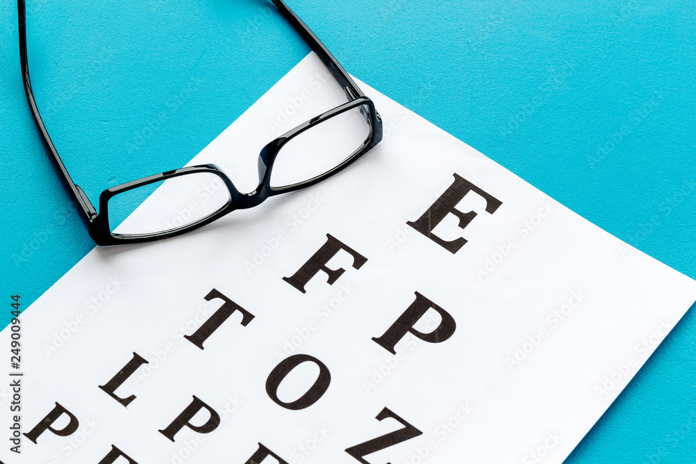 Eye examination. Eyesight test chart and glasses on blue background ...