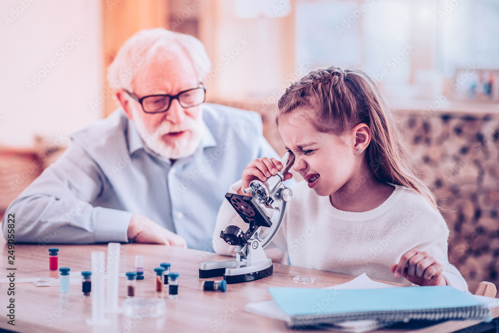 Girl watching in microscope during private lesson Stock Photo | Adobe Stock