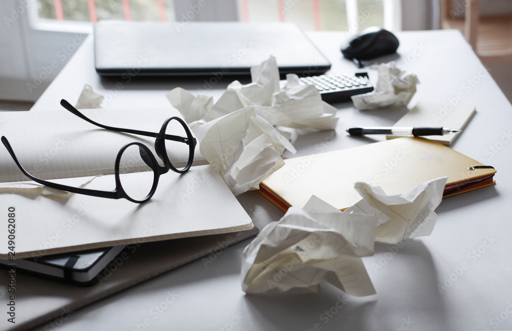 Messy office desk table with notes pencil glasses and crumpled papers ...