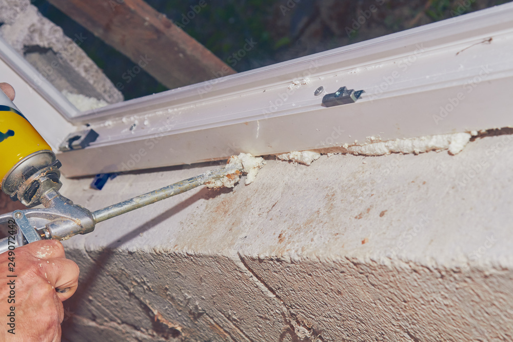 Construction worker puts expandable foam on the PVC window for ...