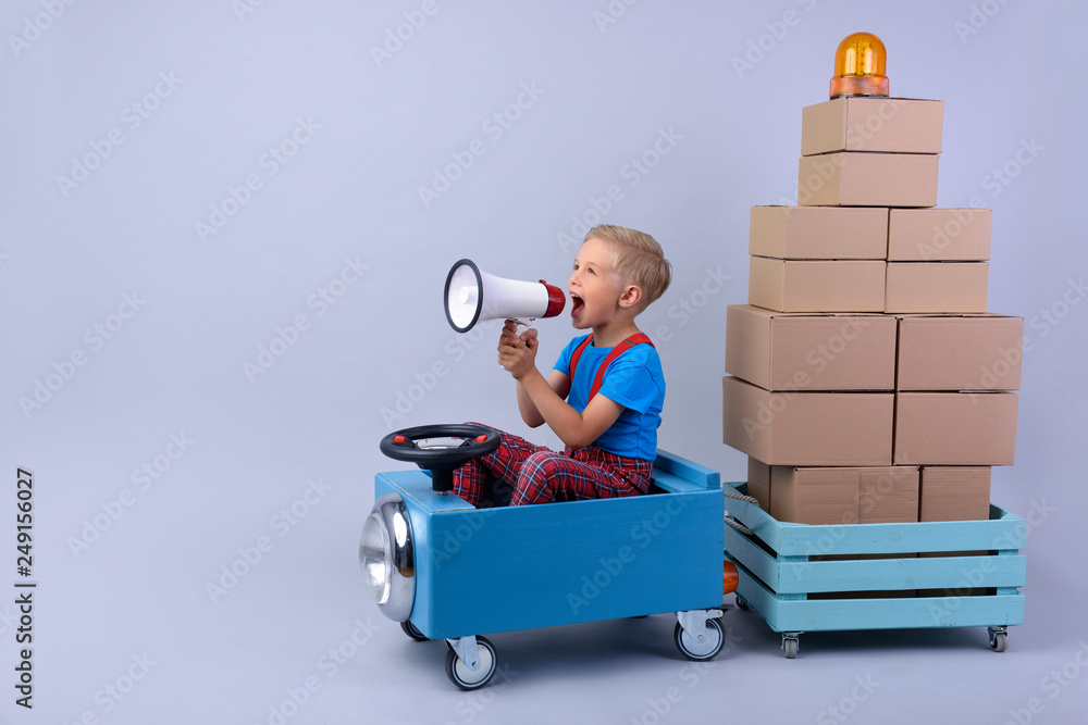 Smiling boy driving blue, fanny car and wagon with small boxes.Happy ...