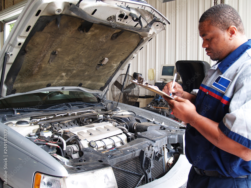 Auto mechanic performing a routine service inspection in a service ...